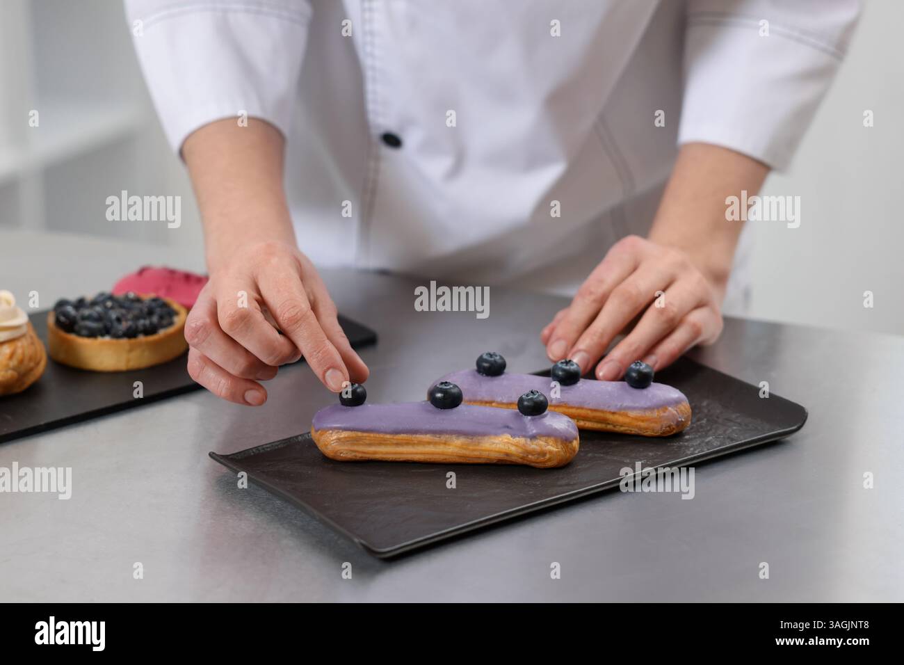 Confectioner decorating eclairs blueberries table hi-res stock ...