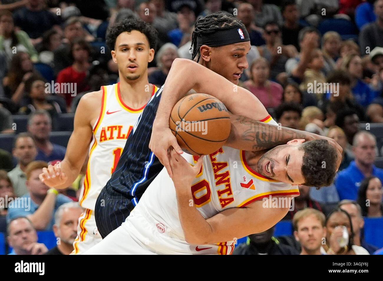Orlando Magic forward Paolo Banchero, center, and Atlanta Hawks forward Georges Niang, right ...