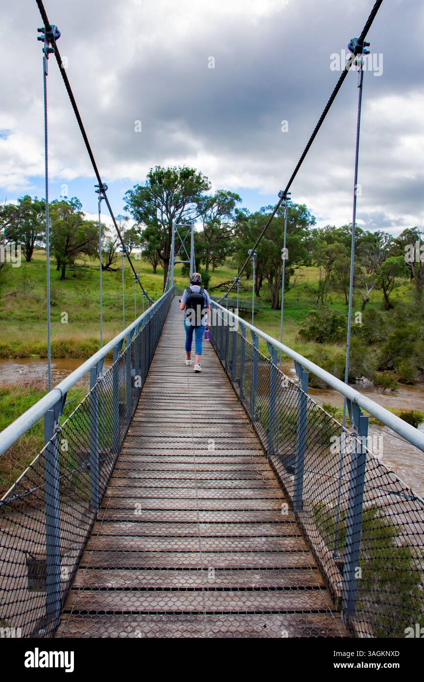 Tourist walking on pedestrian suspension bridge over Apsley River ...