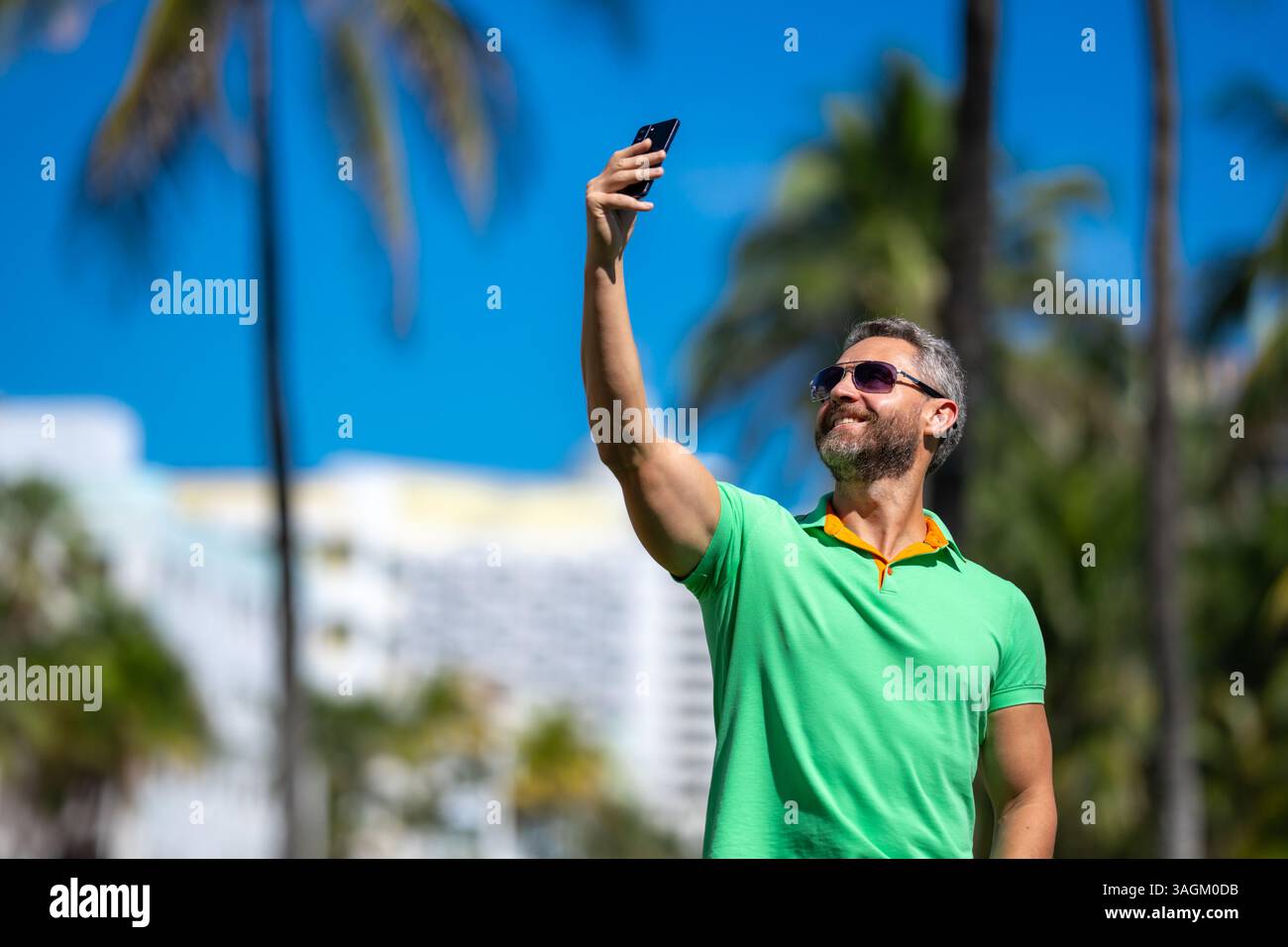 Tourist takes a selfie near palm tree. Man captures a selfie during ...