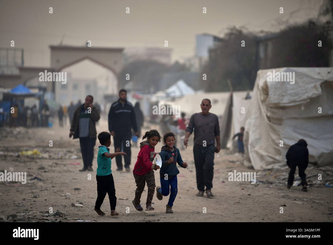 Displaced Palestinians walk by tents at the Islamic University of Gaza ...