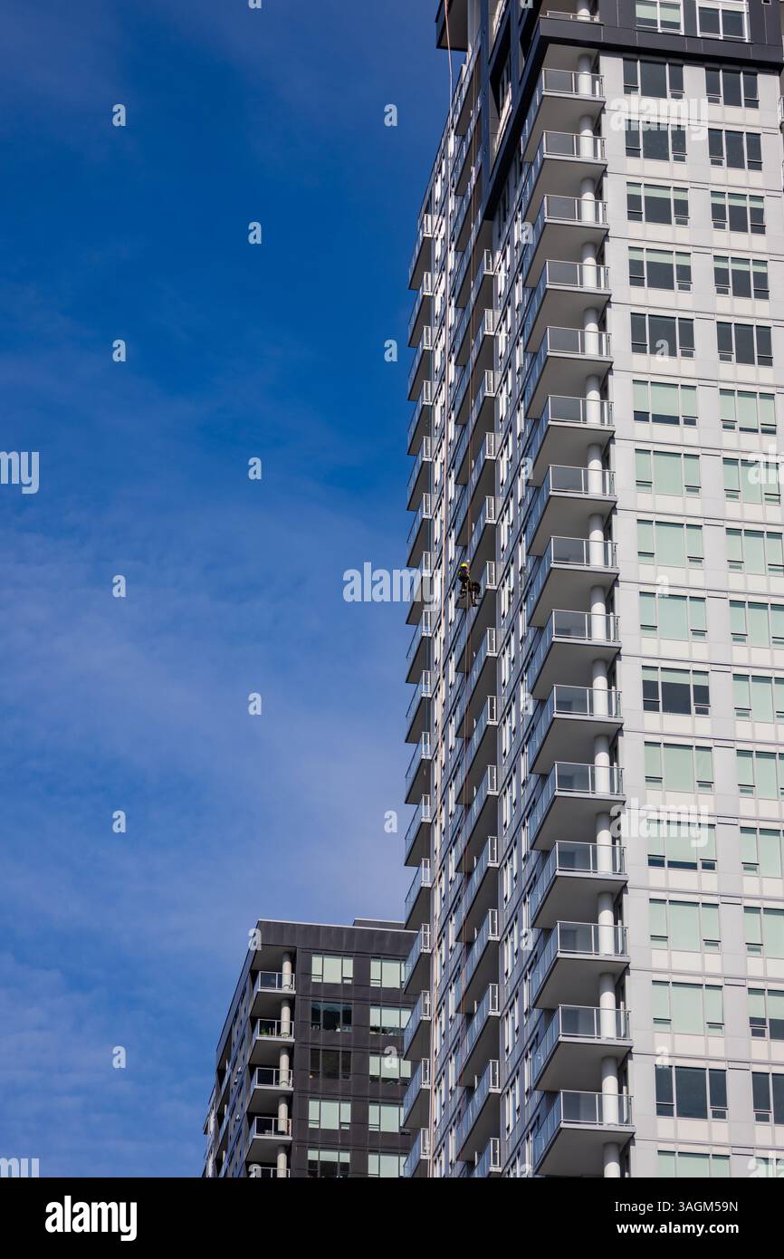A modern high-rise apartment building with balconies under a blue sky ...