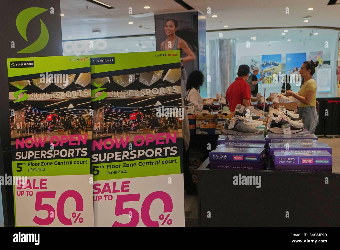 Shoppers are seen behind a sales advertisement at a shopping mall in ...