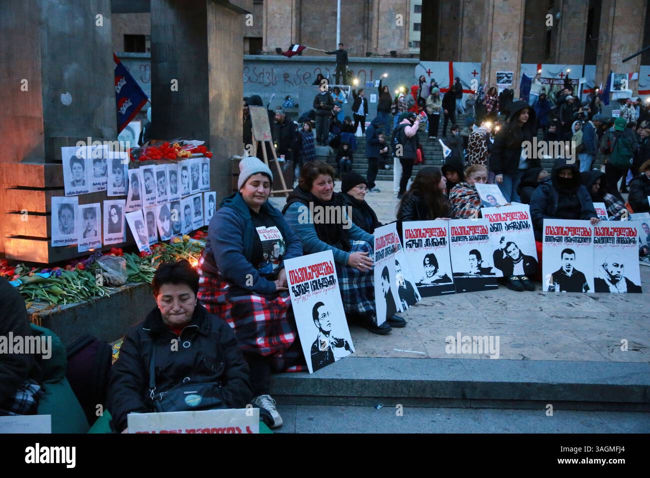 Demonstrators sit with portraits of victims and political prisoners ...