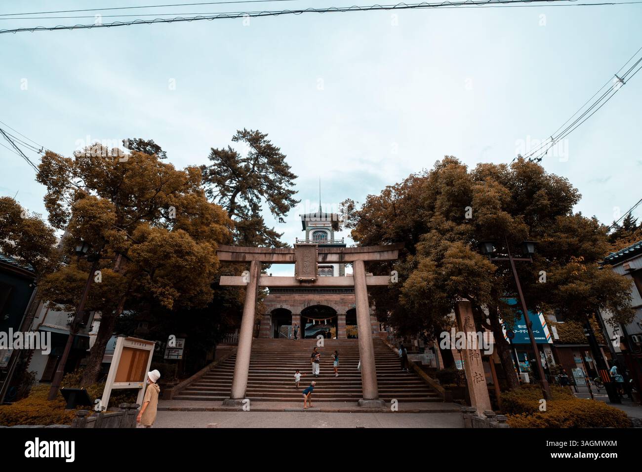 Tourists walk through the iconic torii gate and up the steps to the ...