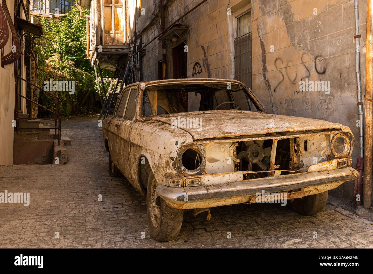 Abandoned vintage car with heavy rust and damage in an old alleyway of ...