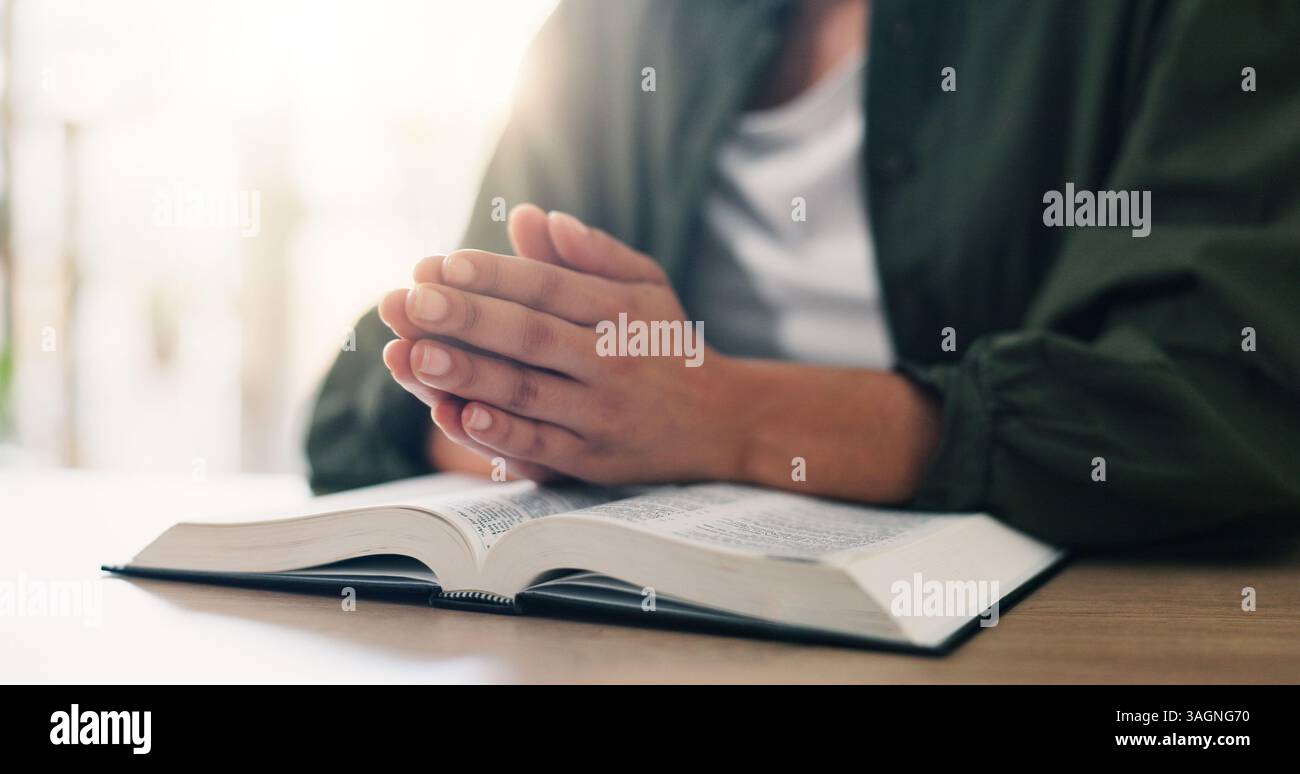 Bible, prayer hands and person reading book in spiritual religion for peace, guidance or ...