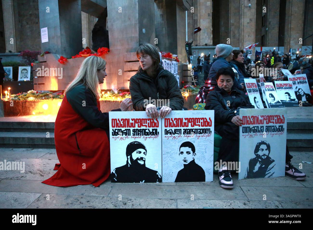 Demonstrators sit with portraits of victims and political prisoners ...