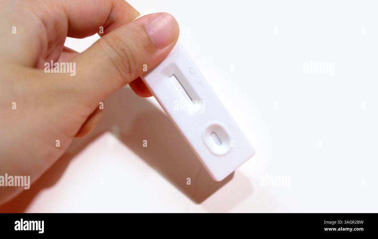 Hand holding a brand new blank self-test kit for Covid flu test. With ...