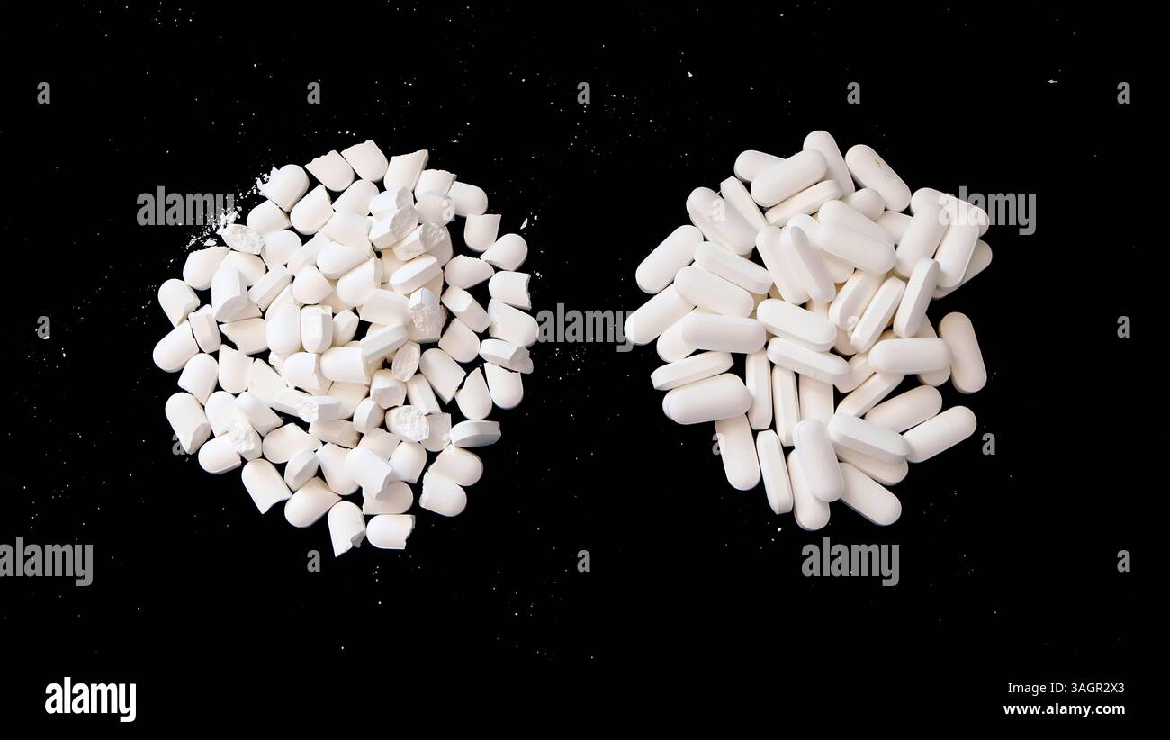 Two piles of white supplement tablets. One pile with whole tablets, and ...