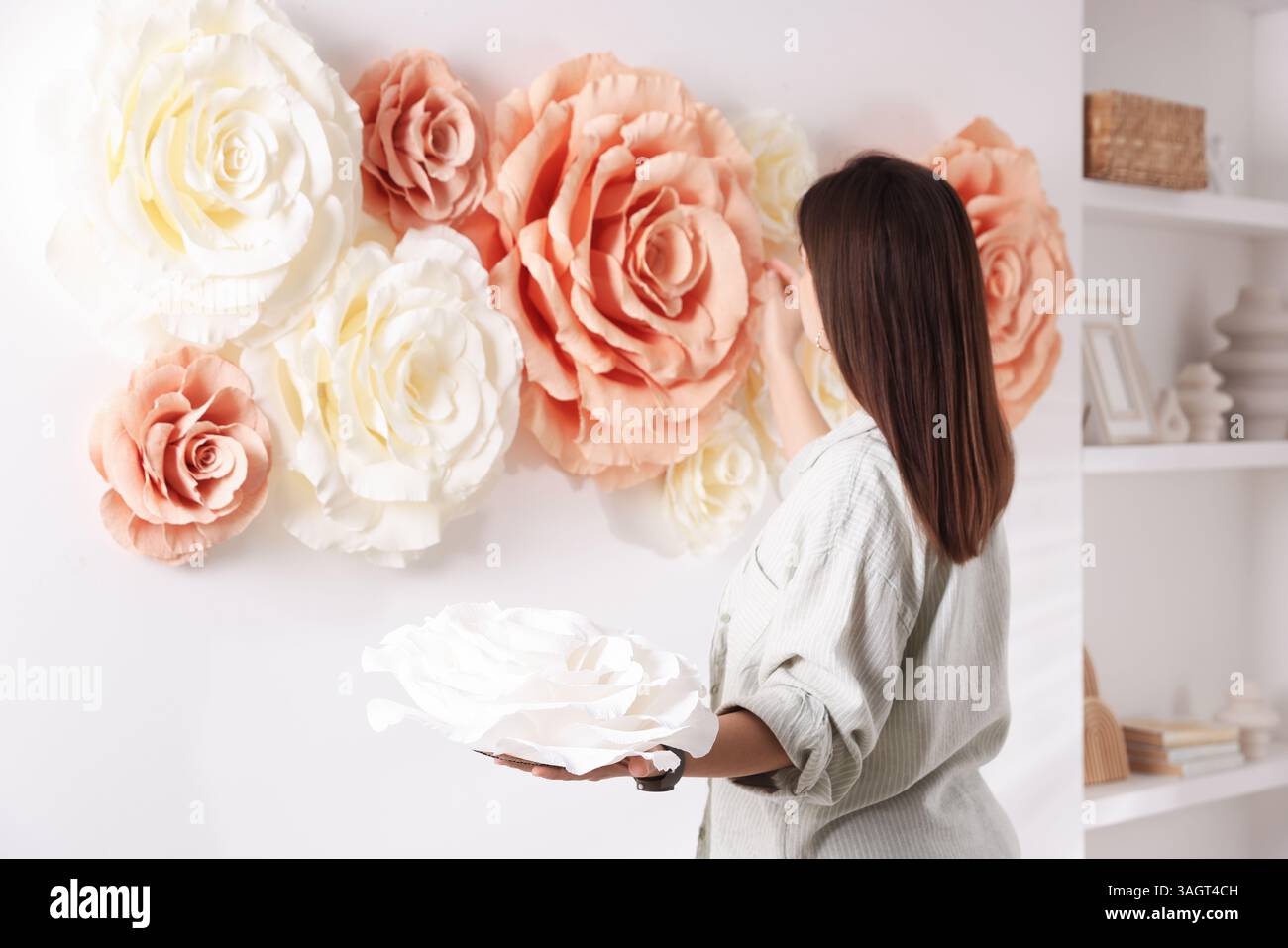 Woman decorating wall with beautiful paper flowers at home Stock Photo ...
