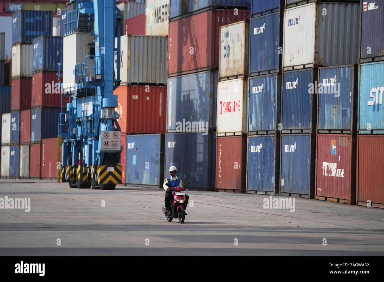 A security guard patrols on a motorbike as shipping containers are ...