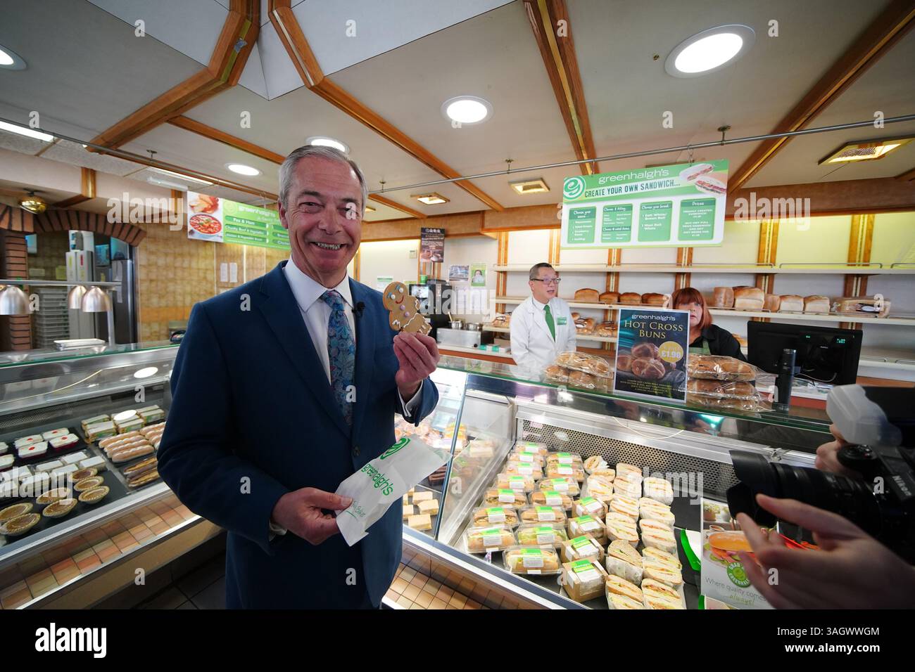 Reform UK leader Nigel Farage holds a gingerbread man during a ...
