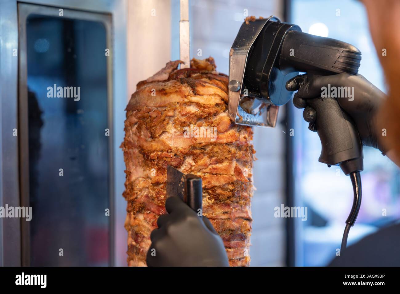 Turkish Cag Kebab cooking in a BBQ. Cook slicing the meat with a ...