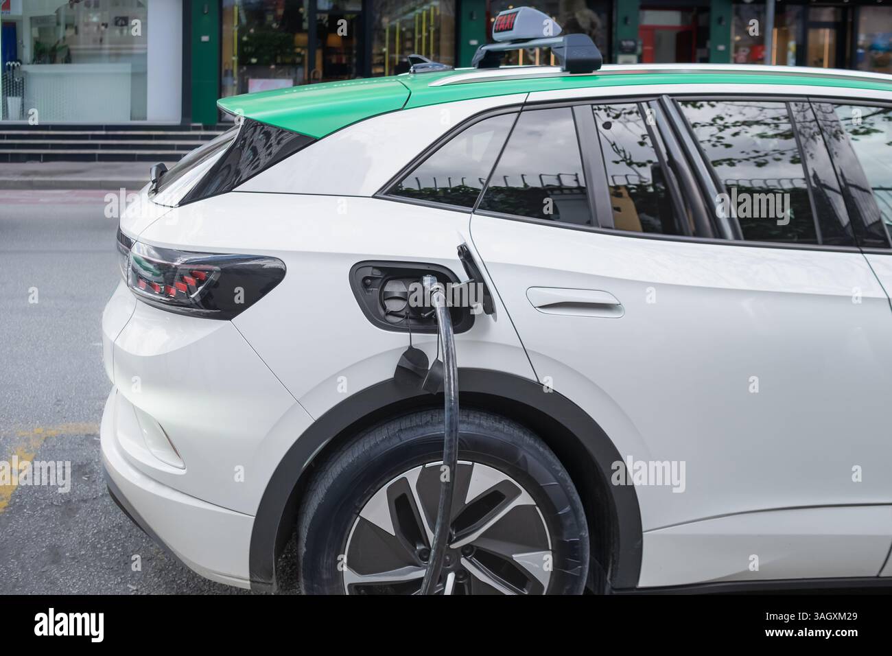Electric vehicle recharges at charging station on the city street ...