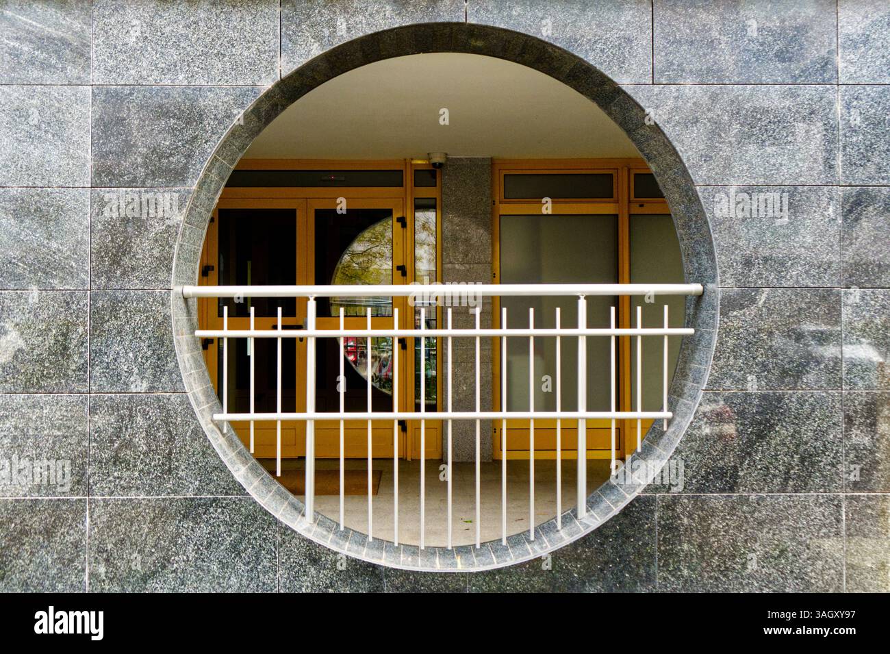 The image shows a circular opening in a stone wall, framing a view of a ...