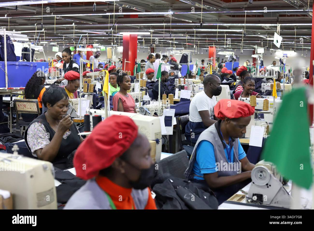 Factory workers operate machine to make garments at United Aryan EPZ ...