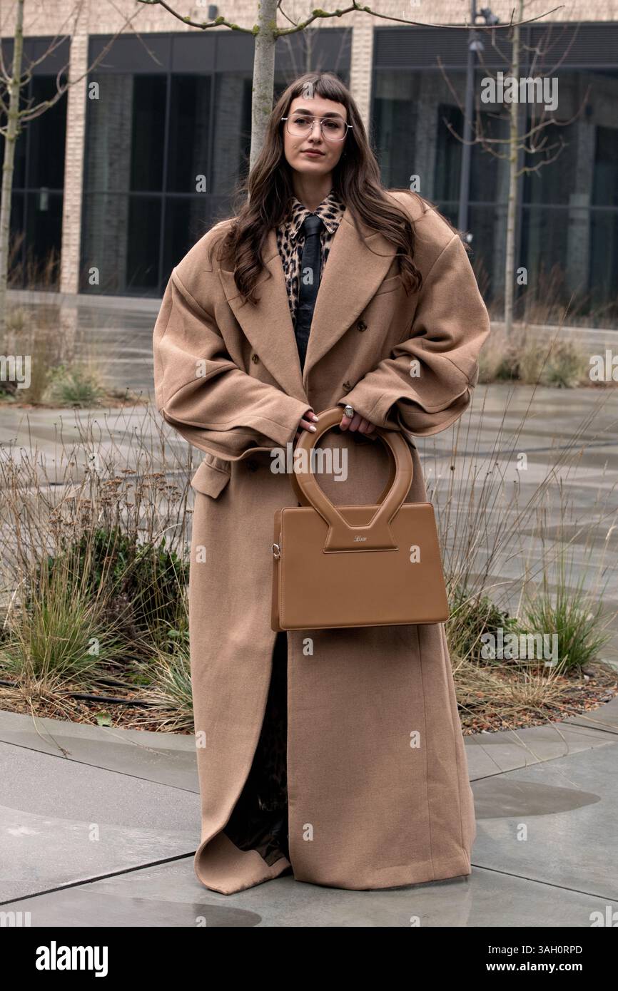Mari Alexander before the Herskind show at CPHFW 25, wearing a brown oversized coat with a ...