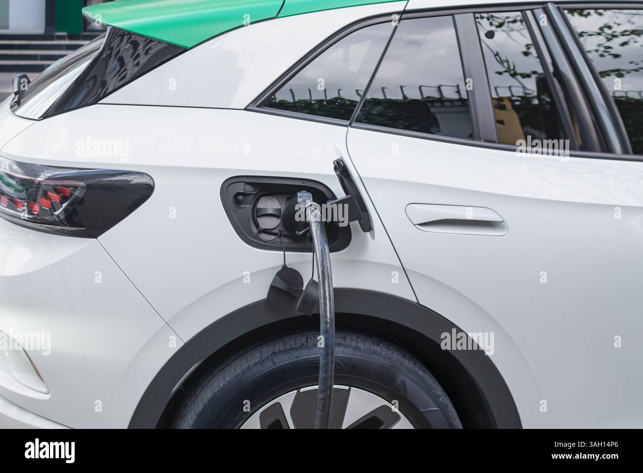 Electric vehicle recharges at charging station on the city street ...