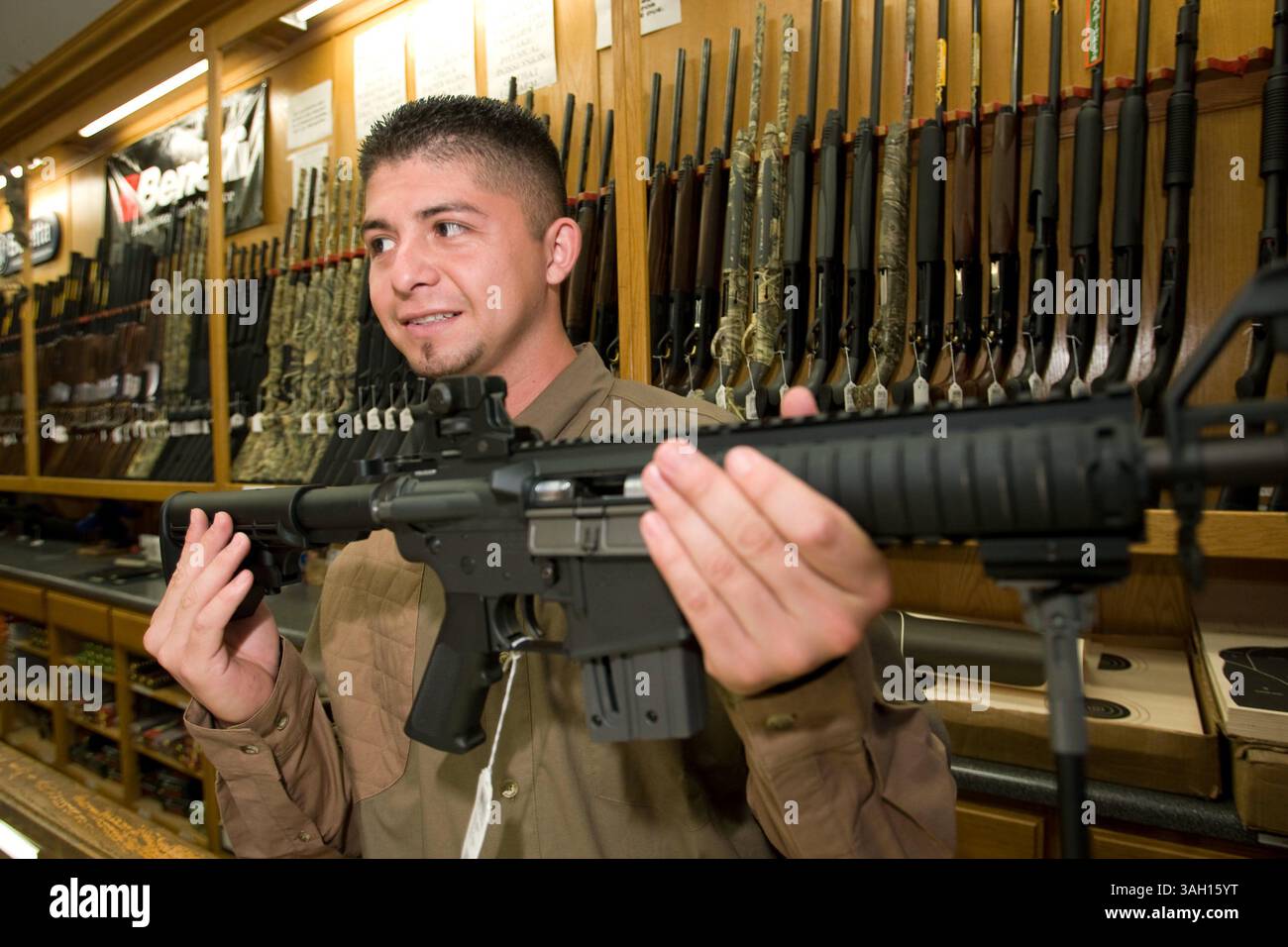 Rigo Rios, employee at The Barnwood Arms Co., holds a Colt M4 rifle in ...