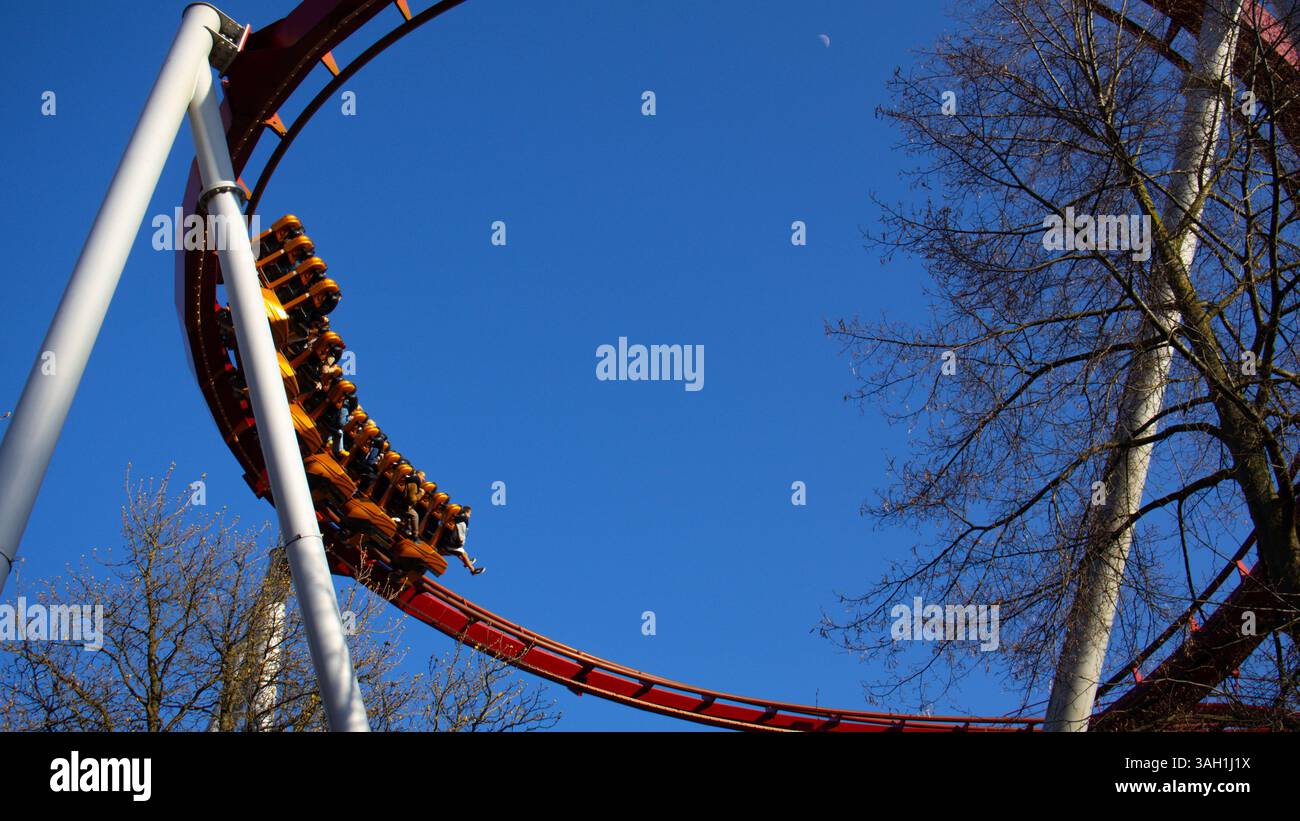 A thrilling roller coaster ride in an amusement park against a clear ...