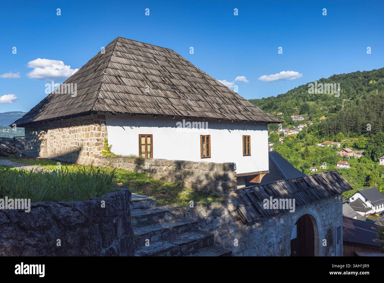 A charming Balkan house featuring a stone foundation, white walls, and ...