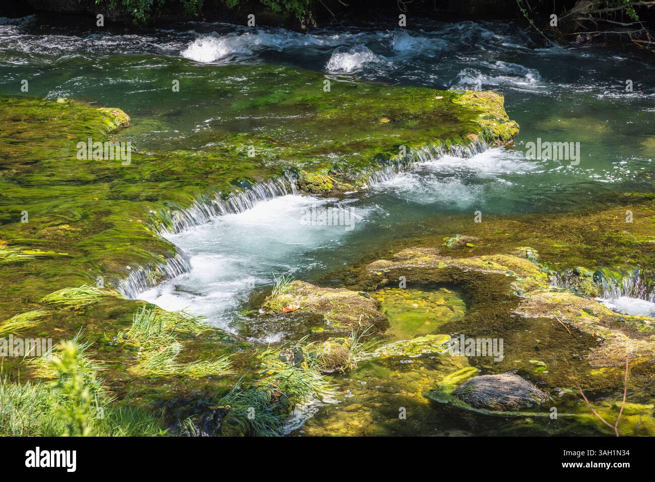 This serene image shows water gently cascading over rocks covered in ...