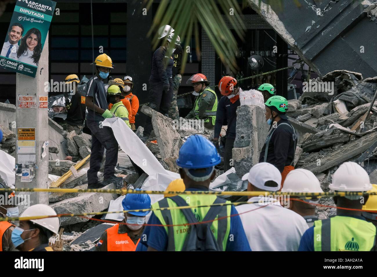 Rescue workers use sheets as they recover bodies from the rubble at the ...