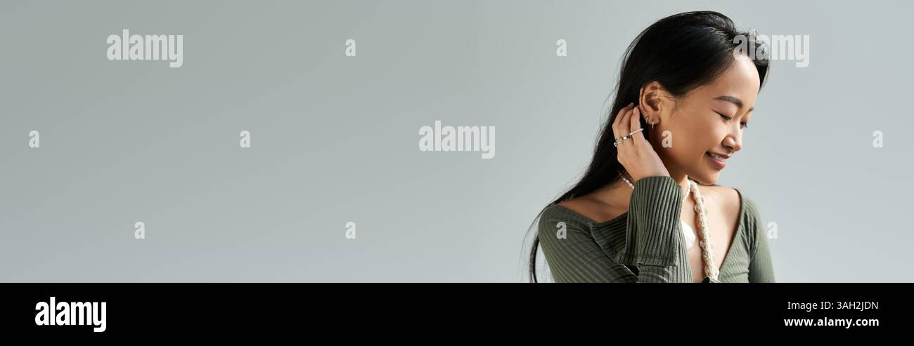 A young beautiful asian woman expresses joy while gently touching her ...