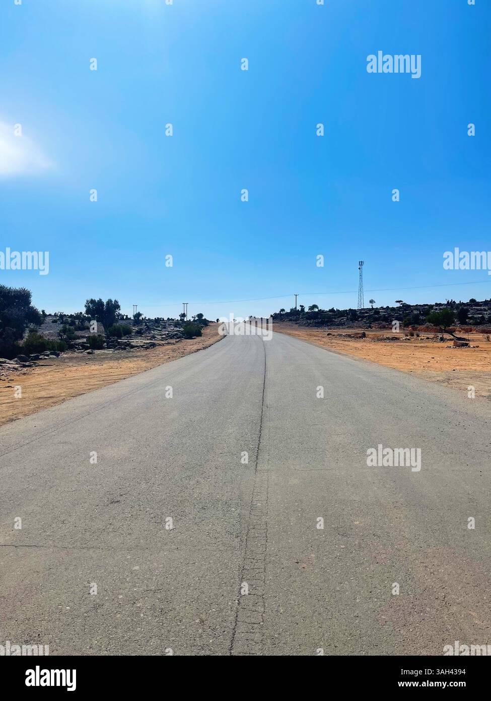 Open Road Through Arid Landscape Under Clear Blue Sky. A vast, empty ...