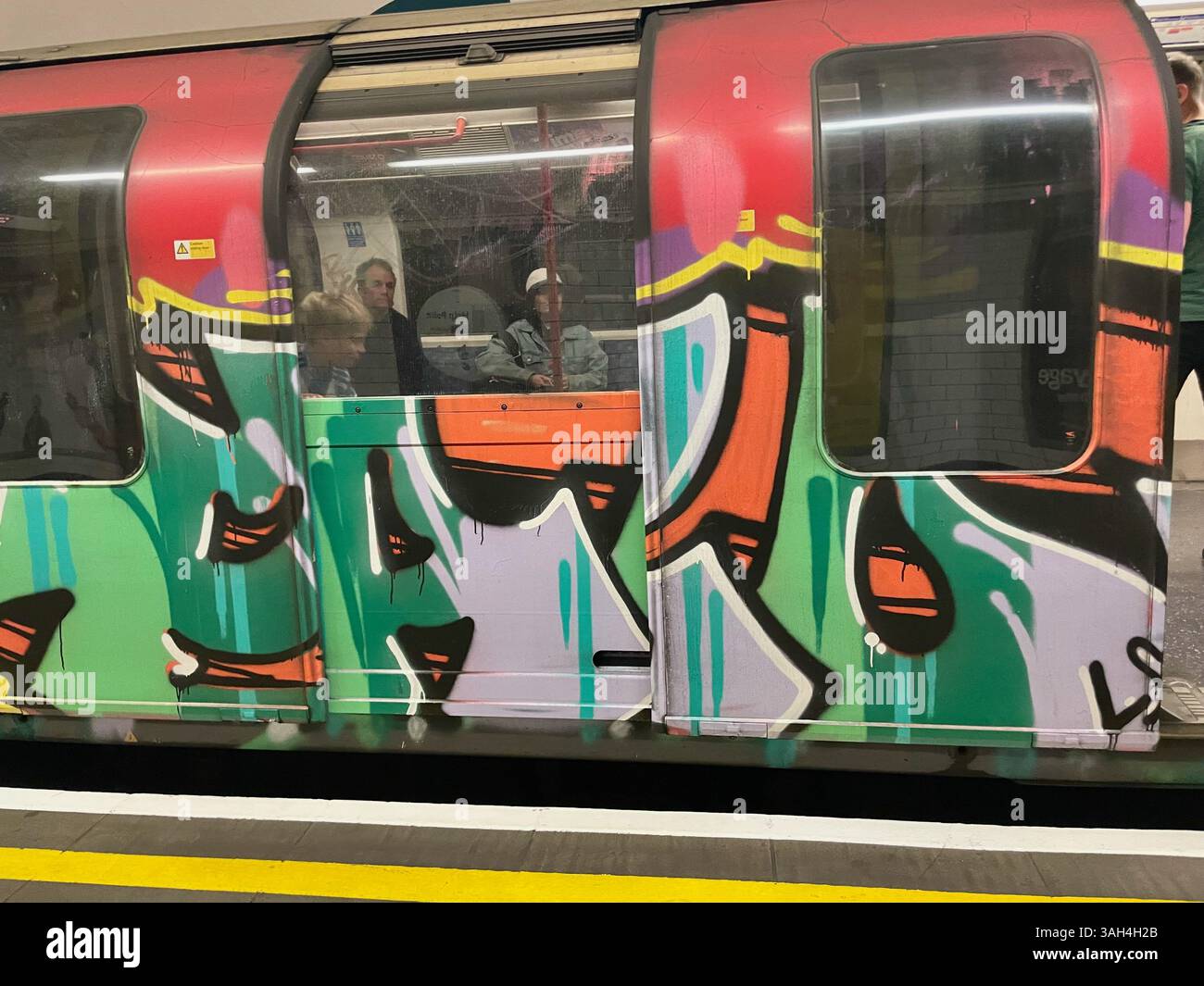 a london underground tube train covered in painted graffiti waits at ...