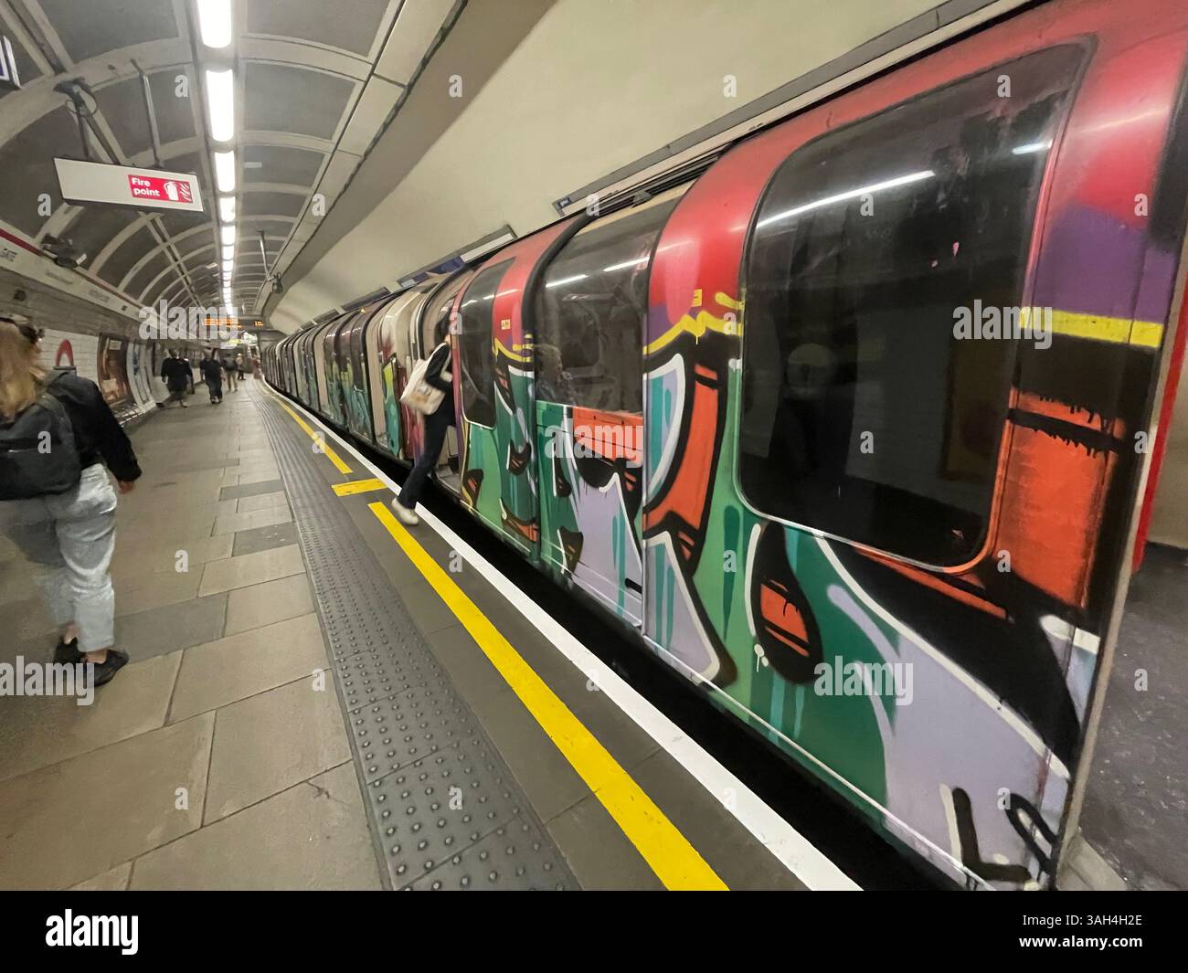 a london underground tube train covered in painted graffiti waits at ...