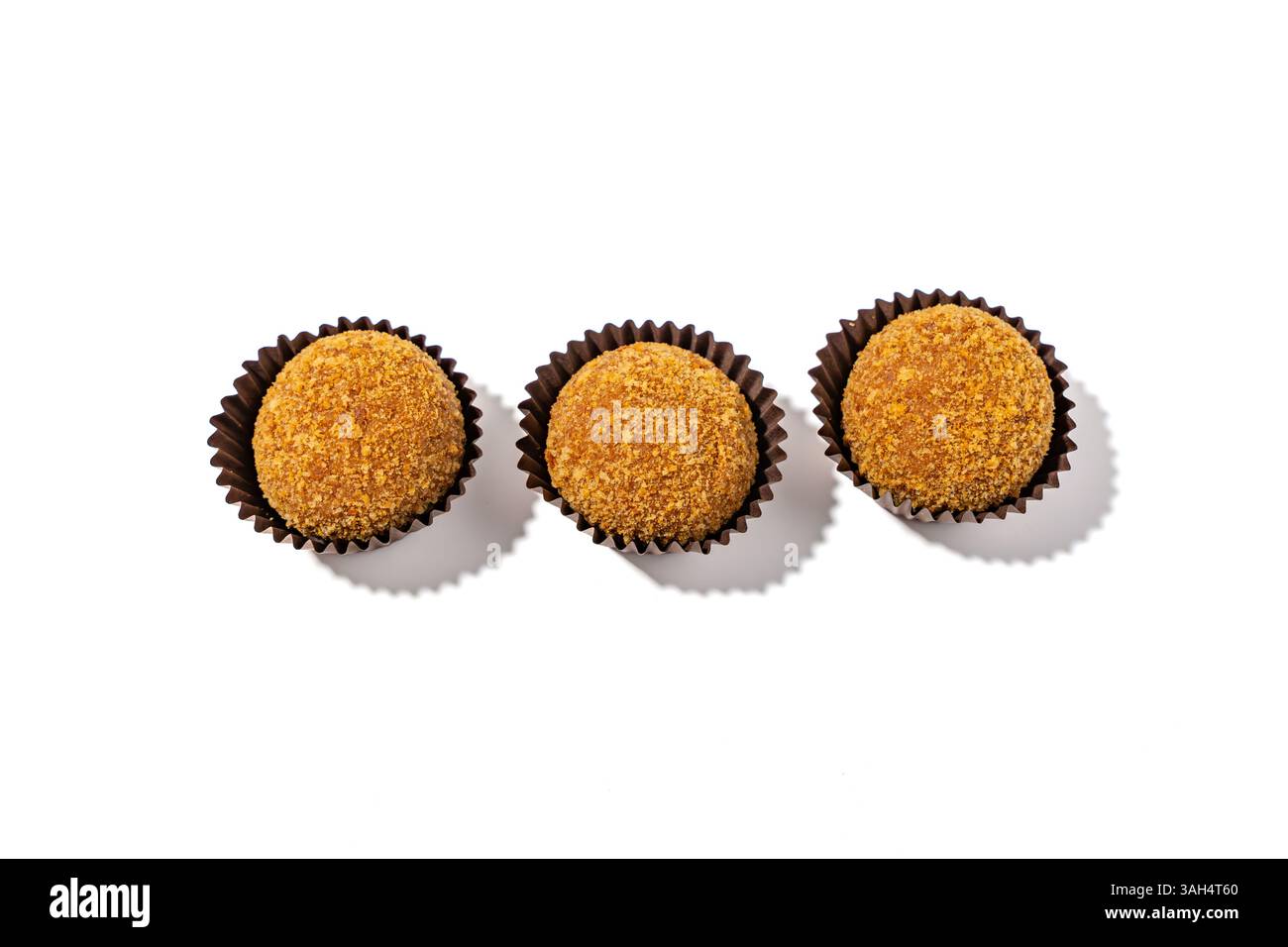 Three small, round, brown pastries in brown paper cups. They are ...