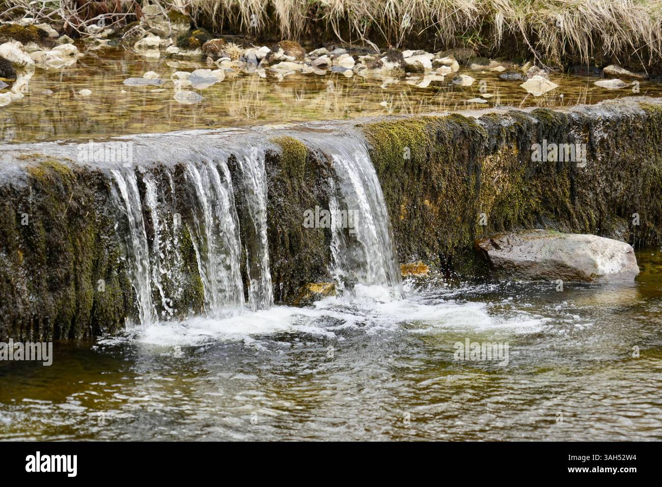 Clear water flowing over a small waterfall in a stream in The Yorkshire ...
