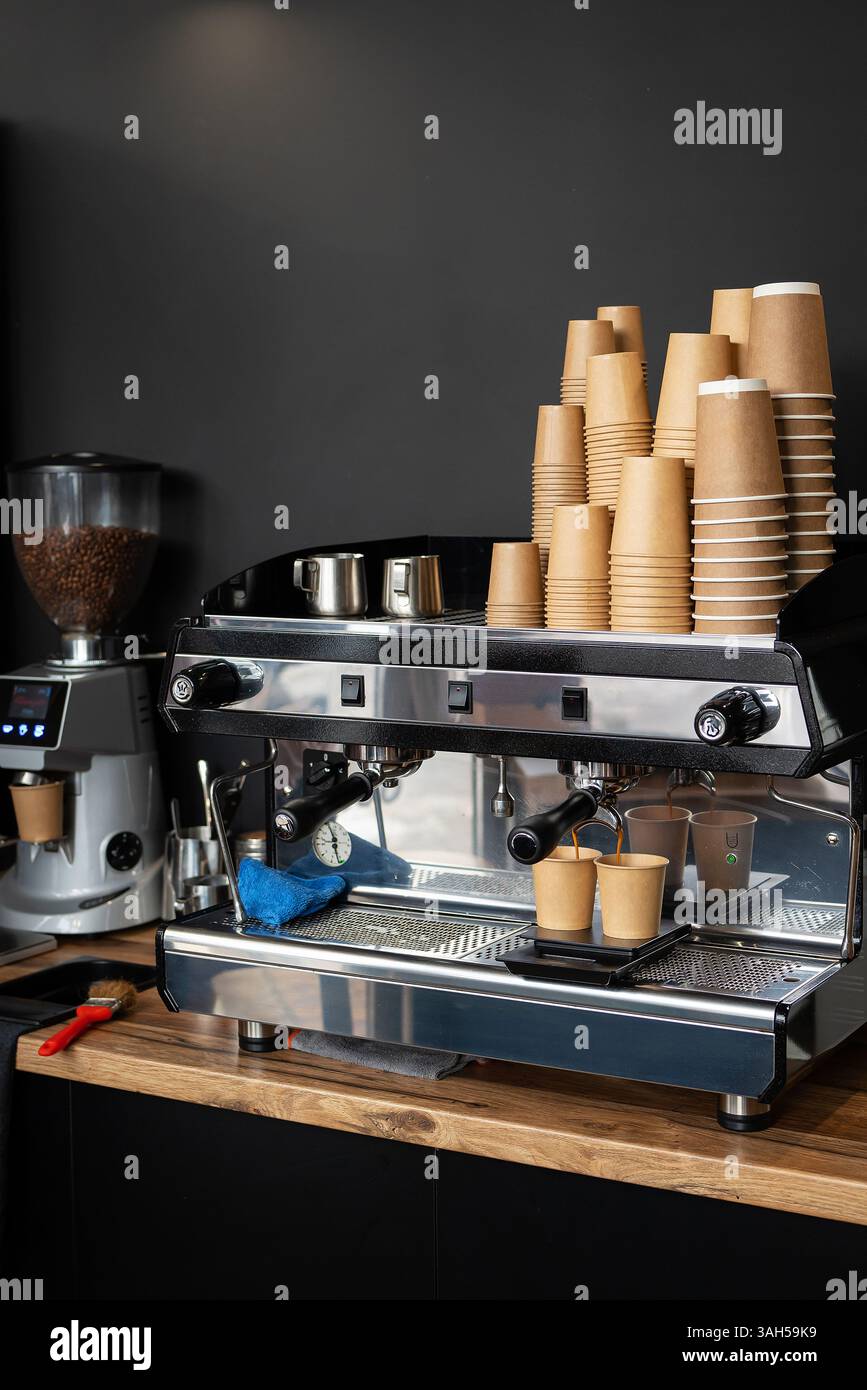 A modern espresso machine prepares coffee in disposable cups, sitting ...