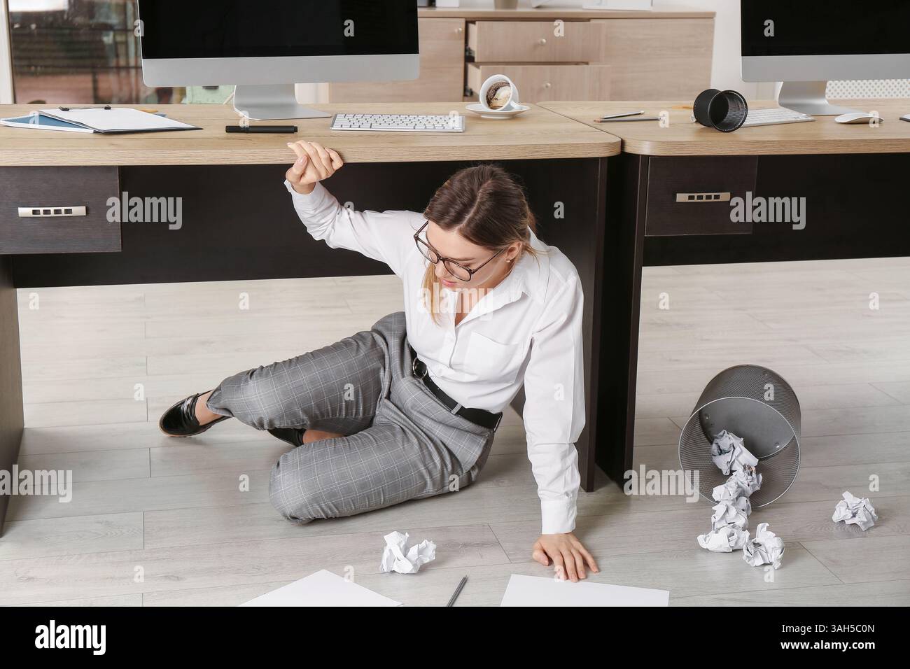 Scared young woman hiding under office desk during earthquake Stock ...