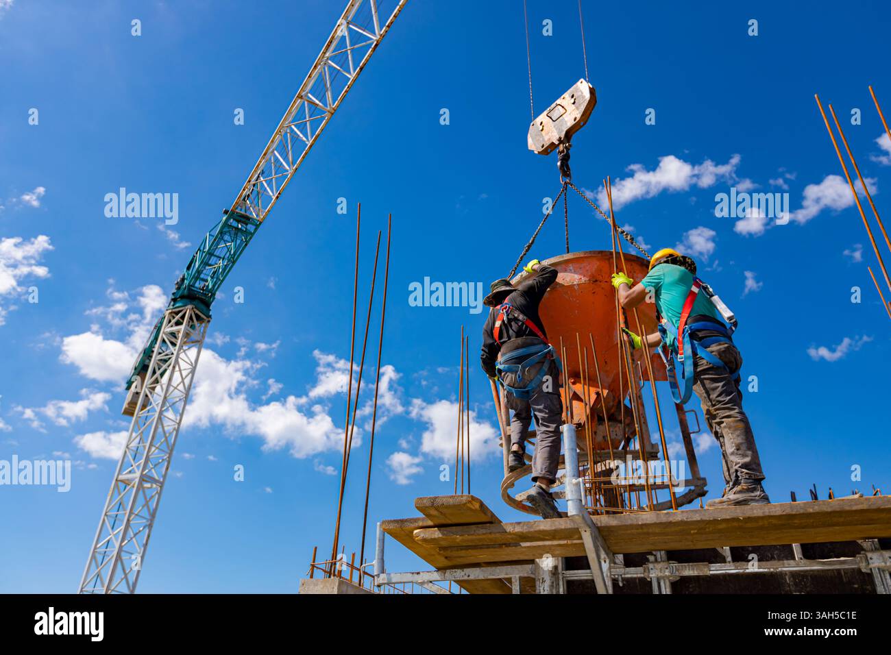 Construction workers are unloading conical metal bucket, transport and ...