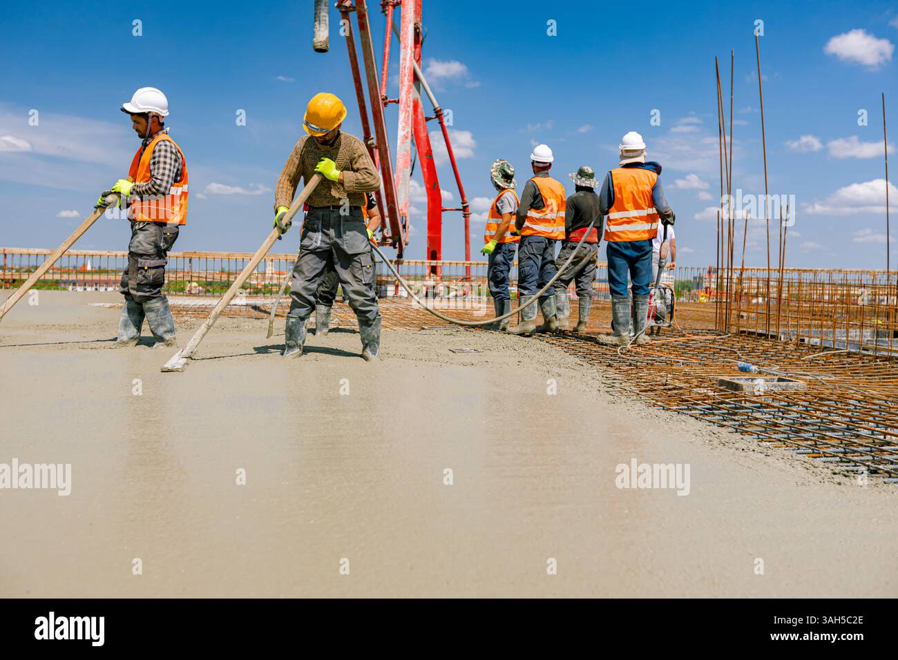 Team of construction workers are pouring and leveling fresh concrete ...