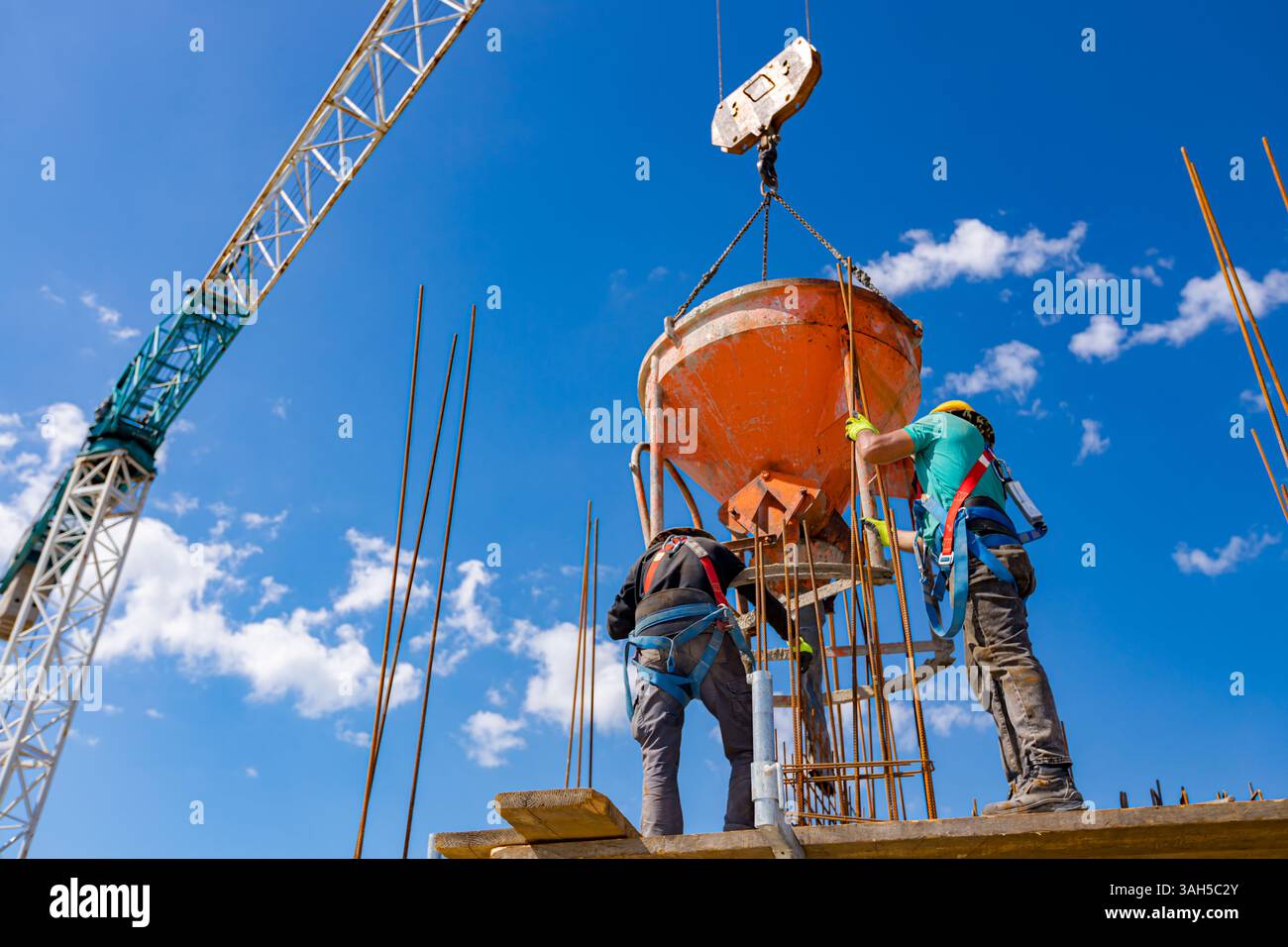 Construction workers are unloading conical metal bucket, transport and ...