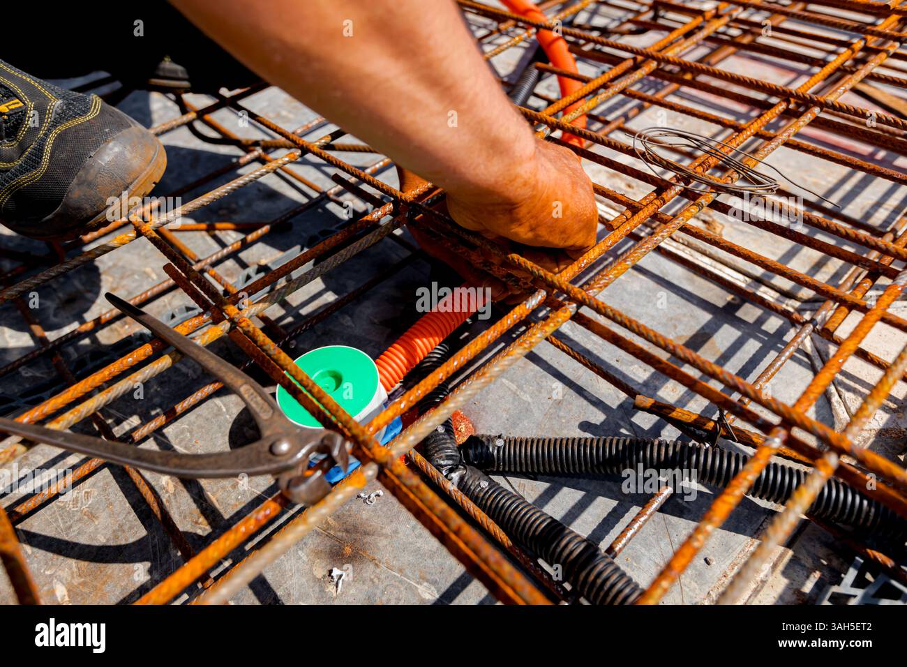 Worker's hands as he assembly protective ribbed plastic hoses, for ...