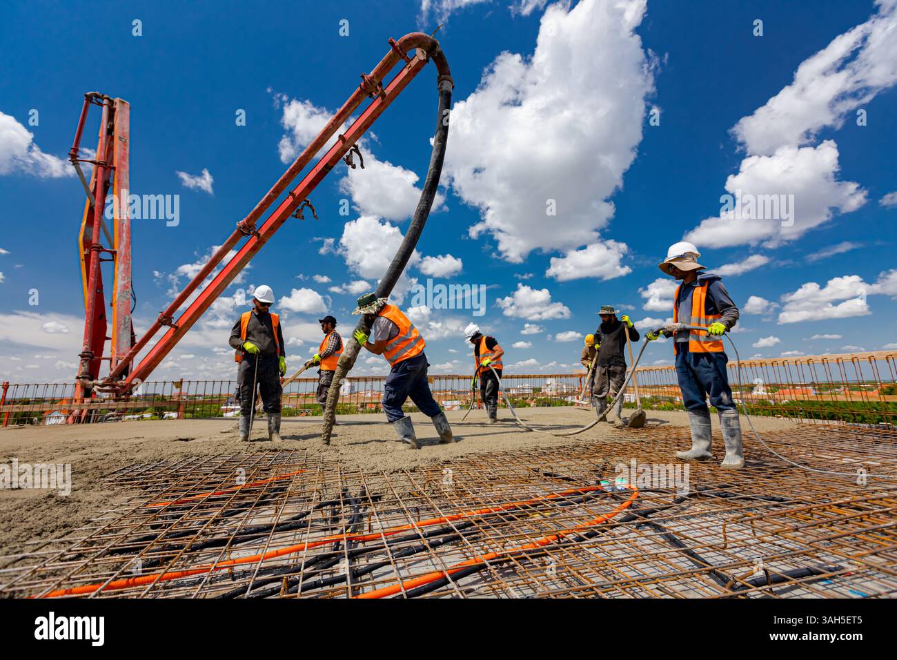 Construction worker in rubber boots is directing pump tube on right ...