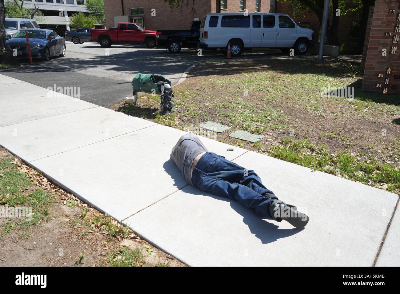 A homeless man takes a morning nap on the public sidewalk outside a ...