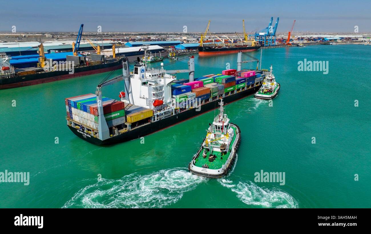 Tug boats maneuver a ship at the port of Umm Qasr, near the city of ...