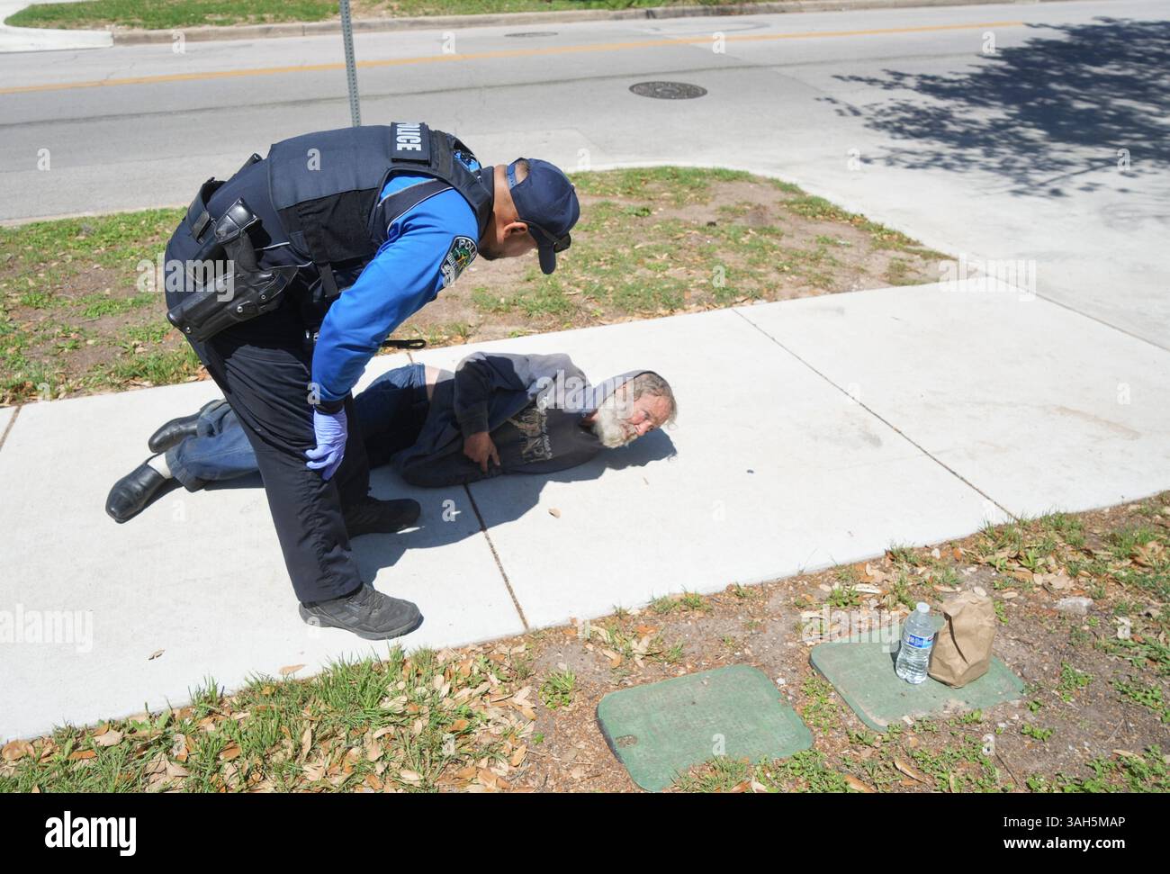 A police officer checks on the health of a homeless man as he wakes ...