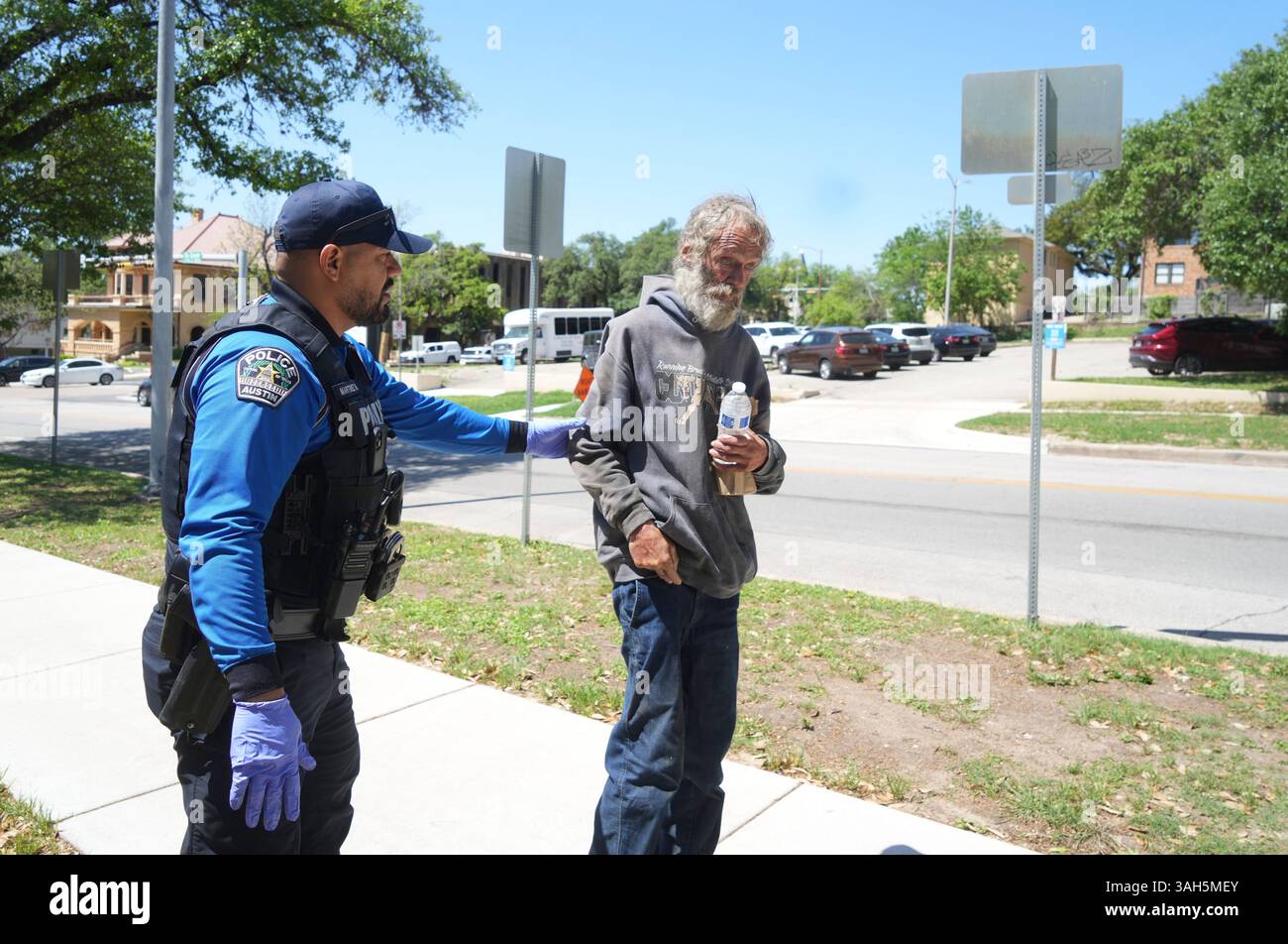A police officer checks on the health of a homeless man as he wakes ...
