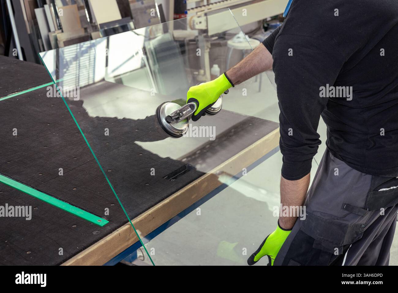 A glazier lifts the glass in the factory using a special glass suction ...