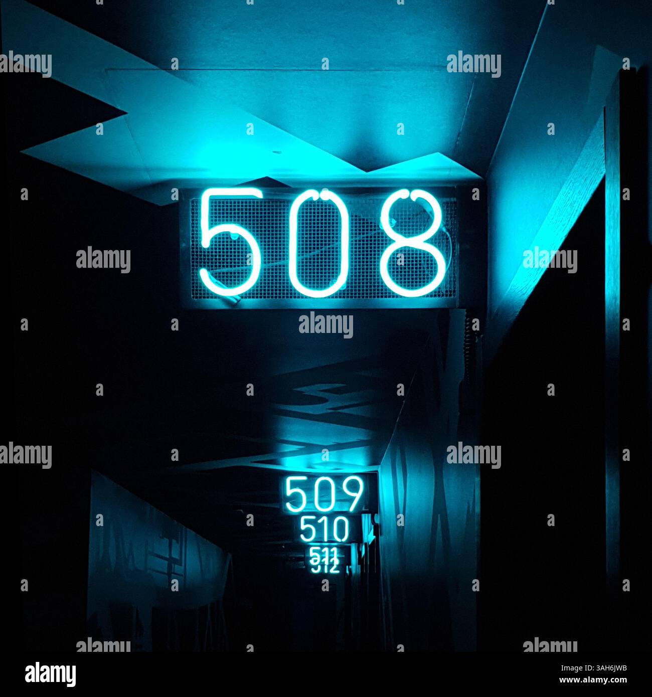Corridor with turquoise neon room numbers. Diminishing perspective view ...