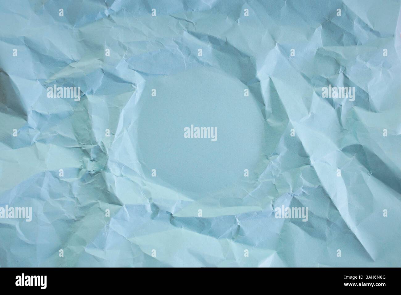 Blue crumpled paper texture with round empty copy space in the middle ...