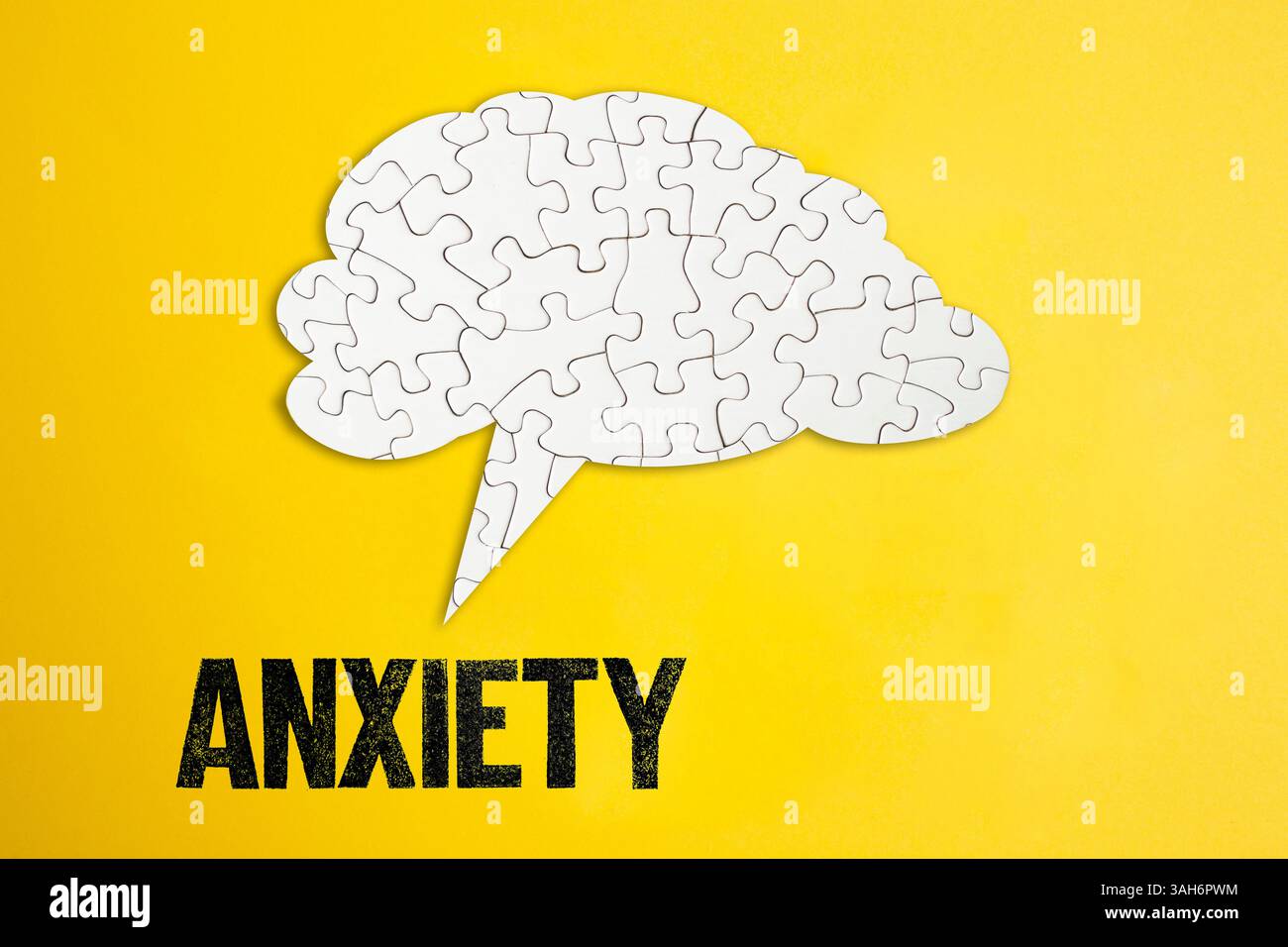 Jigsaw puzzle brain shape speech bubble on yellow cardboard background ...