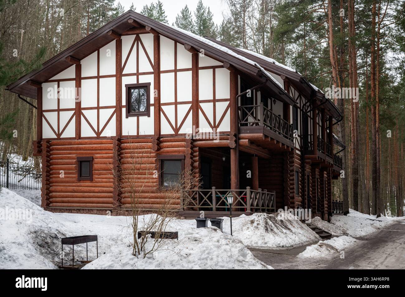 Large two-story brown wooden guest house with balcony against a winter ...